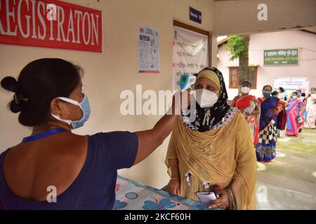 A health worker checks temperature of a citizens who standing in a long ...