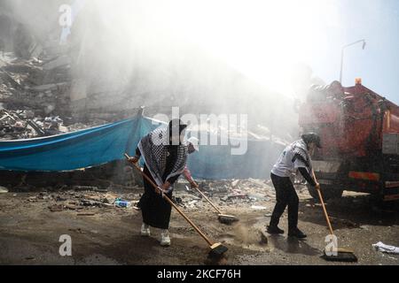 Palestinian volunteers sweep the rubble of buildings, recently ...