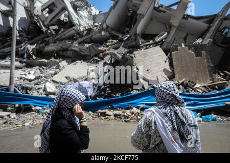 Palestinian volunteers sweep the rubble of buildings, recently ...