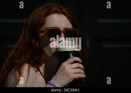 A young woman enjoys a pint of Guinness in a pub in Dublin city center ...