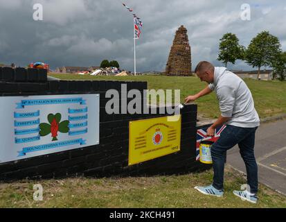 Gary, a local man paints a wall near a typical loyalist bonfire ...