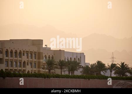 Sunset landscape with remote hotel complex against dark mountain peaks ...