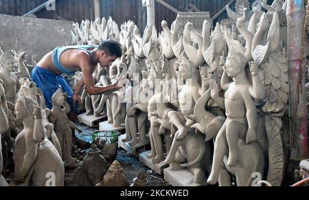 An Indian idol maker adds a mud layer on a semi-finished clay idol of ...