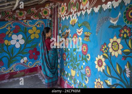 A resident paints alpine on a wall at Alpona village in chapainawabganj ...