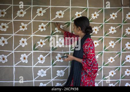 A resident paints alpine on a wall at Alpona village in chapainawabganj ...