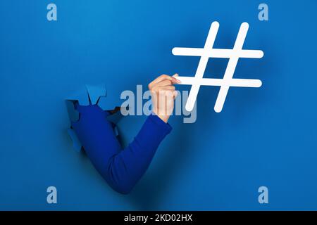 hand holding hashtag sign over blue background, social media concept ...