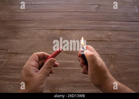 Image of the hands of a man who lights the fuse of a firecracker with a ...