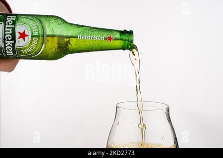 A Bottle of Heineken Beer pouring into a glass on a black background ...