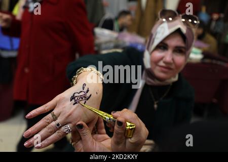 A Palestinian tattoo artist draws a traditional henna tattoo on a woman ...
