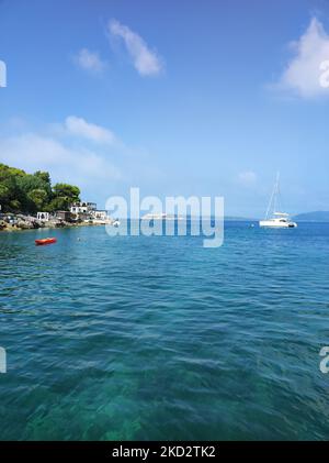A vertical shot of the sea with a sailboat against the background of ...