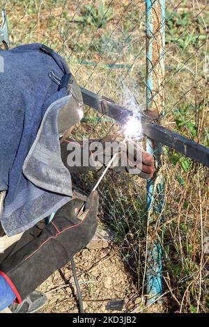 Laborer in protective mask welds manually metal frame Stock Photo - Alamy