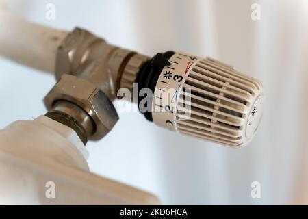 A thermostat of central heating with a cutout of cast iron radiator ...