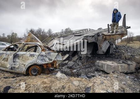A man stands on the wreckage of the bridge destroyed during Russian ...
