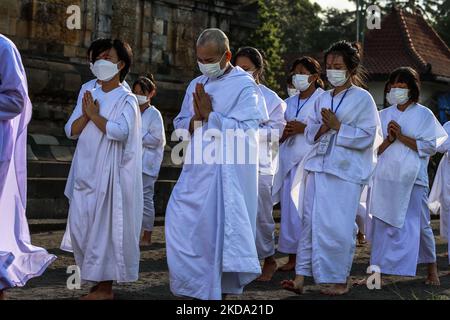 Buddhist monks walk around Mendut temple during the holy water ceremony ...