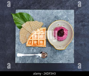 Hibiscus organic ice cream with waffle on stone plate with spoon and ...