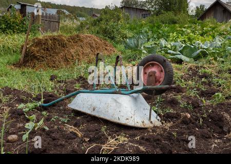 overturned wheelbarrow in the garden. wheelbarrow lying on the ground ...
