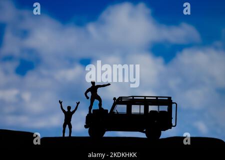 Miniature toys of two men celebrate triumphantly at the mountain ...