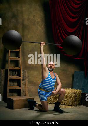 Strength. Overweight man, retro circus strongman wearing striped sports ...