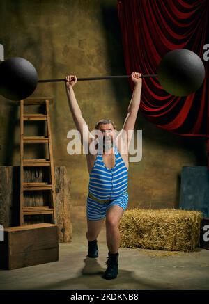 Strength. Overweight man, retro circus strongman wearing striped sports ...