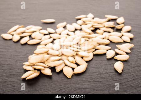 Unpeeled raw pumpkin seeds on slate stone, macro, top view Stock Photo ...
