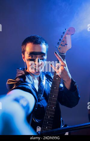 Musician sticking out tongue and doing rock and roll hand gesture on ...