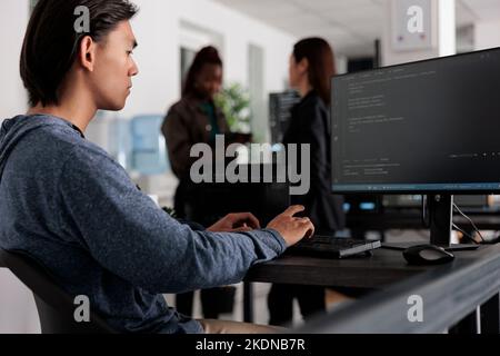 Database admin typing programming code on computer with multiple ...
