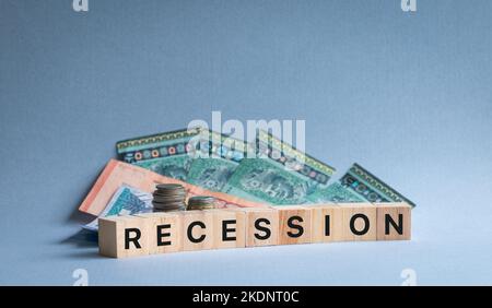 Recession, word on wood block, and paper currency and coins at the ...