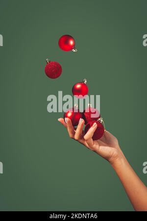Beautiful woman's hand juggling Christmas baubles on dark green ...
