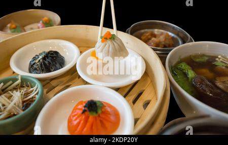 Die cut of Xiao long bao, set dim sum with a set brass teapot on on ...