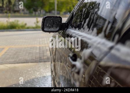 Washing mirrors in a car with active foam. Car wash Stock Photo - Alamy