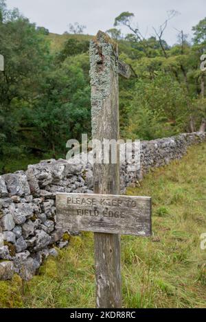 Wooden sign "Please keep to the field edge" in the Deepdale in the ...