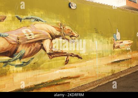 A mural of two greyhounds and an eagle chasing a power boat on a wall ...