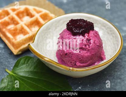 Hibiscus organic ice cream with waffle on stone plate with spoon and ...