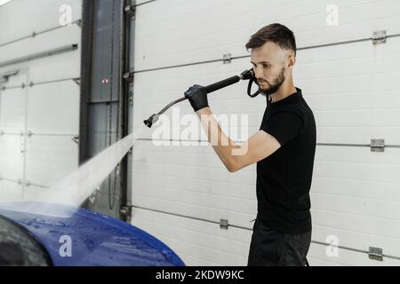 Car washer does full body car wash. Process of spraying foam on the car ...