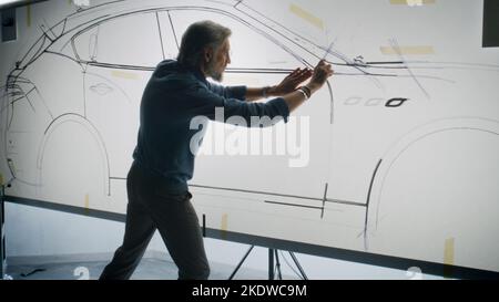 Mature automotive male designer drawing car body sketch with marker at ...