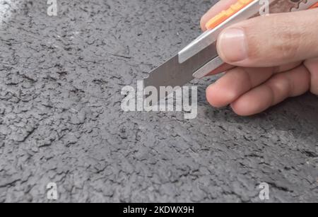 A dry hand holding box cutters and slicing Stock Photo - Alamy