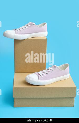 Cardboard boxes with sneakers on color background Stock Photo - Alamy