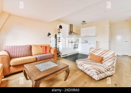 Table with chairs and flowers located near lounge area and kitchen in ...