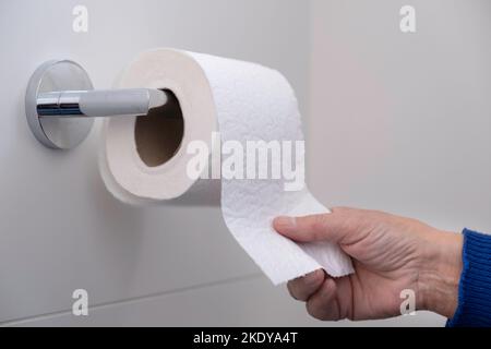 Hand tears a sheet of paper from a toilet paper roll. Motion blur of ...