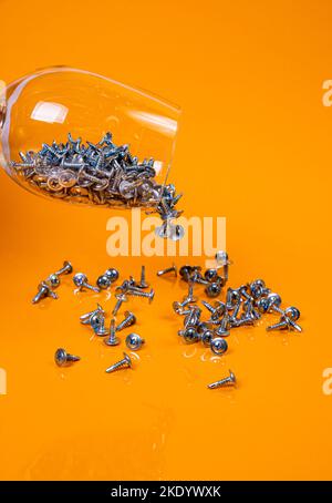 Dropped Many metal self-tapping screws made of steel in a glass, in ...