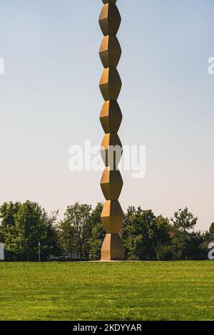 A vertical shot of Infinity Column monument against blue sky in a park ...