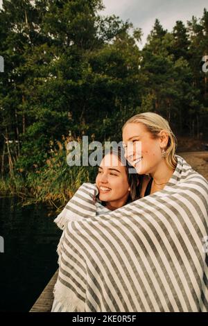 Young cheerful female with white towel on head holding small jar with ...