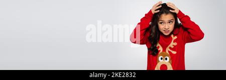 Scared child in red sweater looking away and covering head isolated on ...