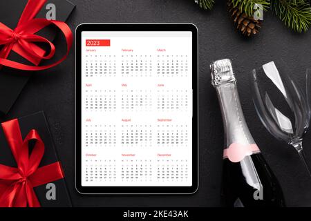 Tablet with calendar, champagne and Christmas decor. Xmas device screen ...