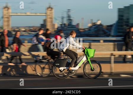 A woman commuting on a Lime electric hire bike across London Bridge ...