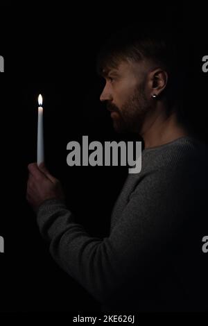 Man holding a burning candle in his hands, elegant young man with ...