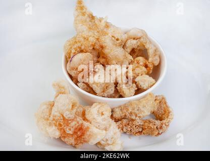 Perfectly crisp, pork rind or crackling in white bowl with copy space ...