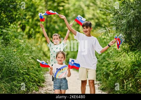 Three kids hold slovenian flags in Triglav National Park, Slovenia ...