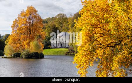 The Temple of Flora at Stourhead framed by trees and foliage in golden ...