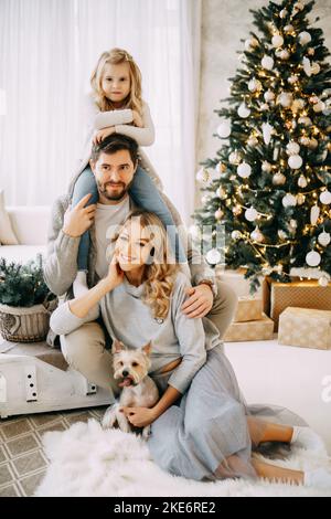 Happy family: mom, dad and pet. Family in a bright New Year's interior ...